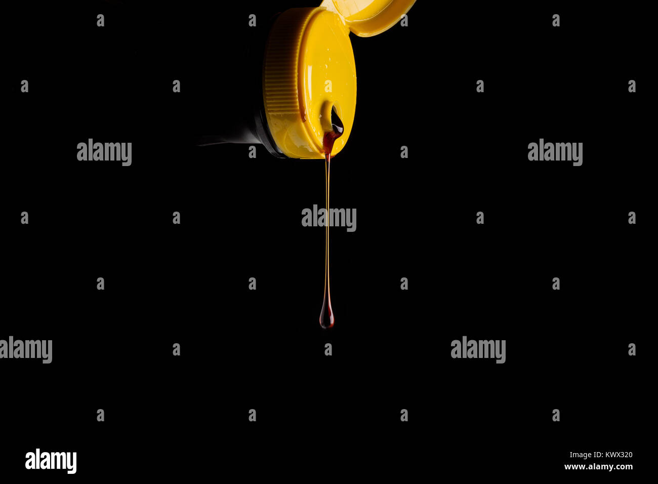 Drop of syrup with it's bottle on black background Stock Photo - Alamy