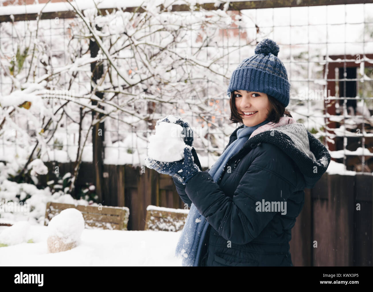 Little girl makes snowballs in a backyard, enjoying the first snow in ...