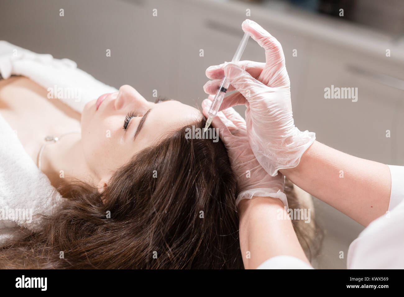 Handsome woman receives an injection in the head. The procedure makes ...
