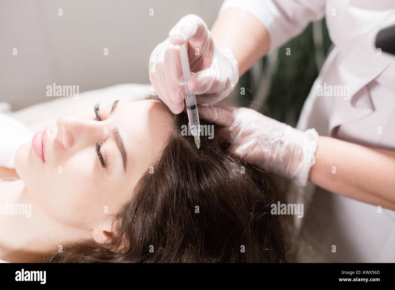 Handsome woman receives an injection in the head. The procedure makes ...