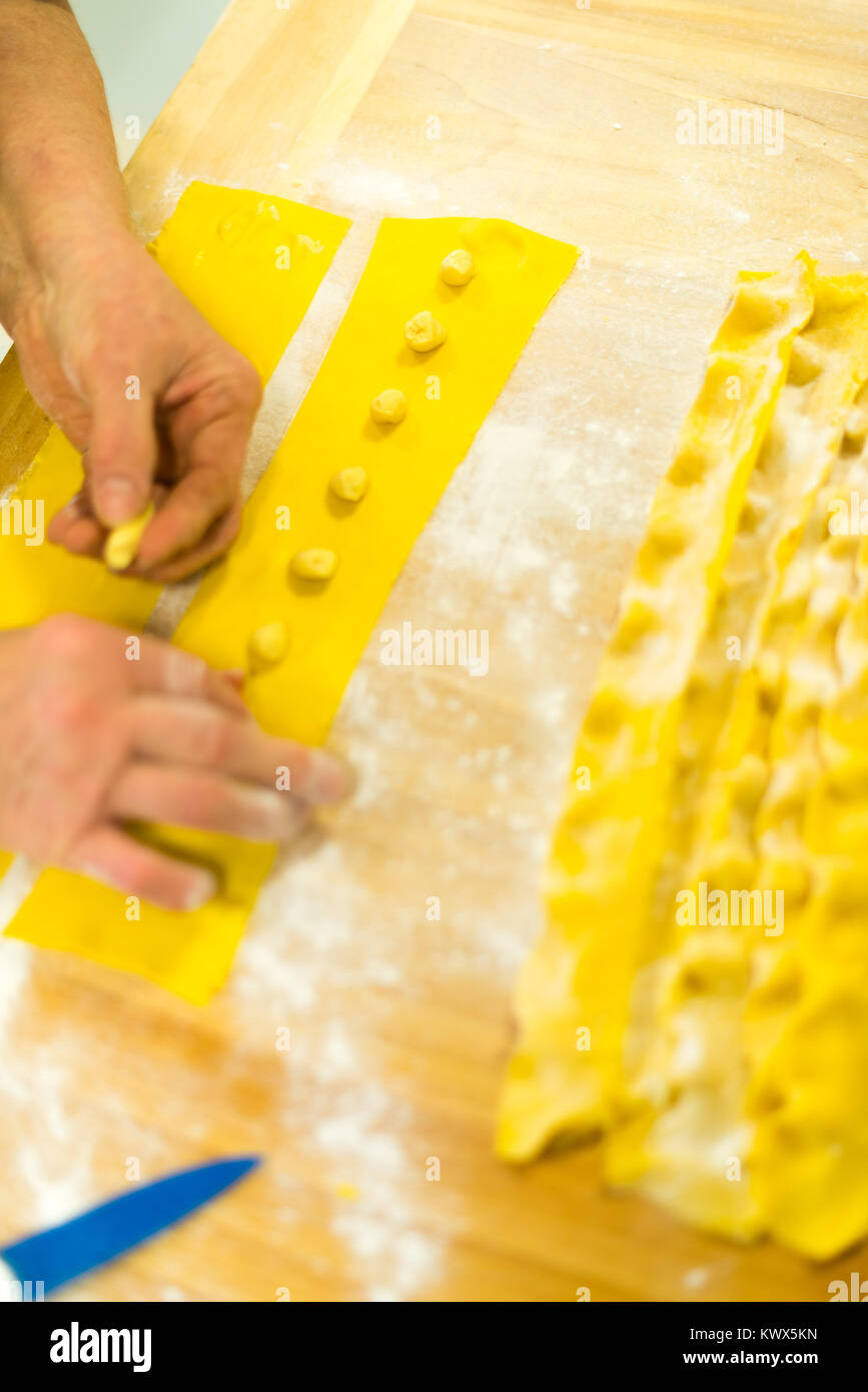 Senior 70s 80s pastry chef lady cutting and stuffing italian pasta ...