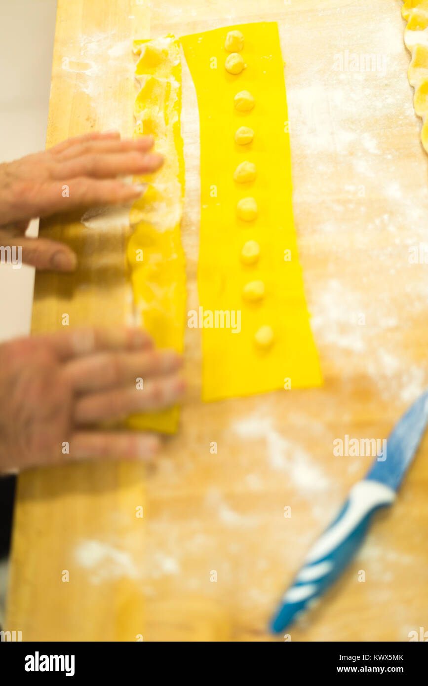 Senior 70s 80s pastry chef lady cutting and stuffing italian pasta ...