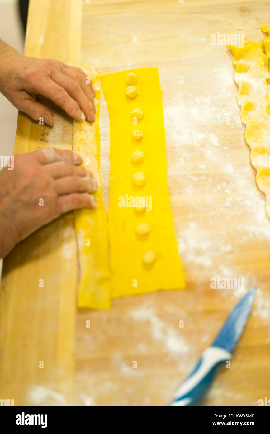 Senior 70s 80s pastry chef lady cutting and stuffing italian pasta ...