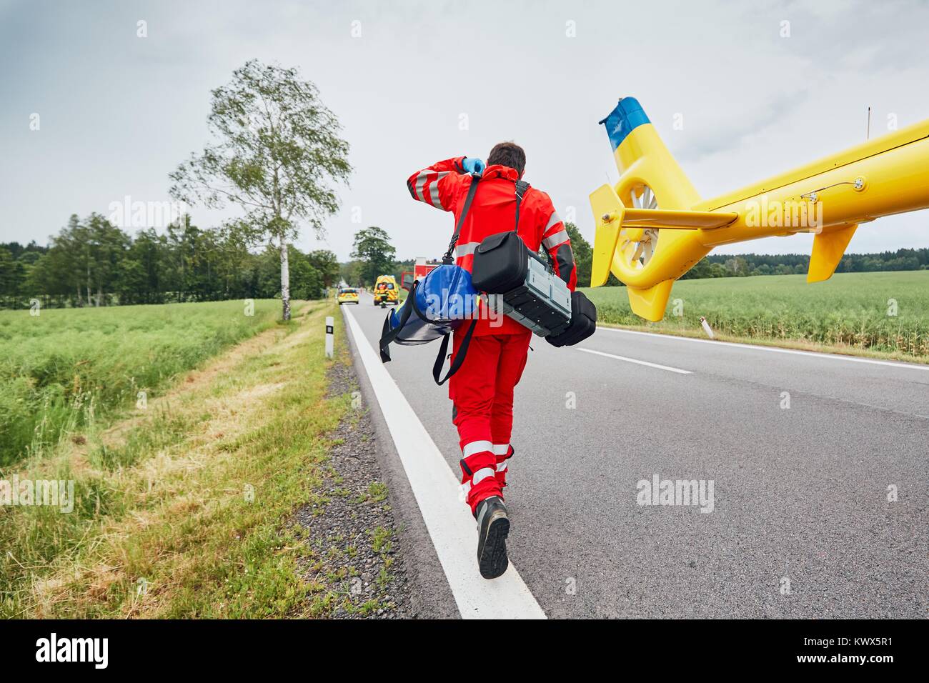 Doctor with defibrillator and other equipment running from helicopter ...