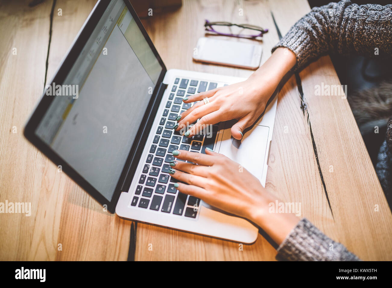 Close-up of the hand of a young girl in a gray sweater use laptop ...