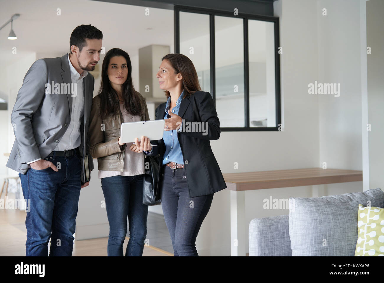 Couple with real-estate agent visiting modern house Stock Photo - Alamy
