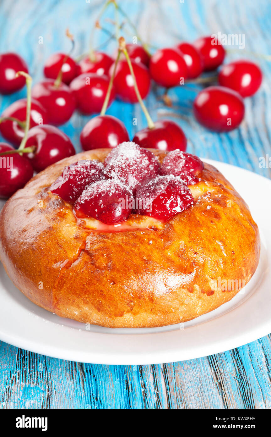 Fresh homemade bun with sweet cherry on a blue wooden background Stock ...
