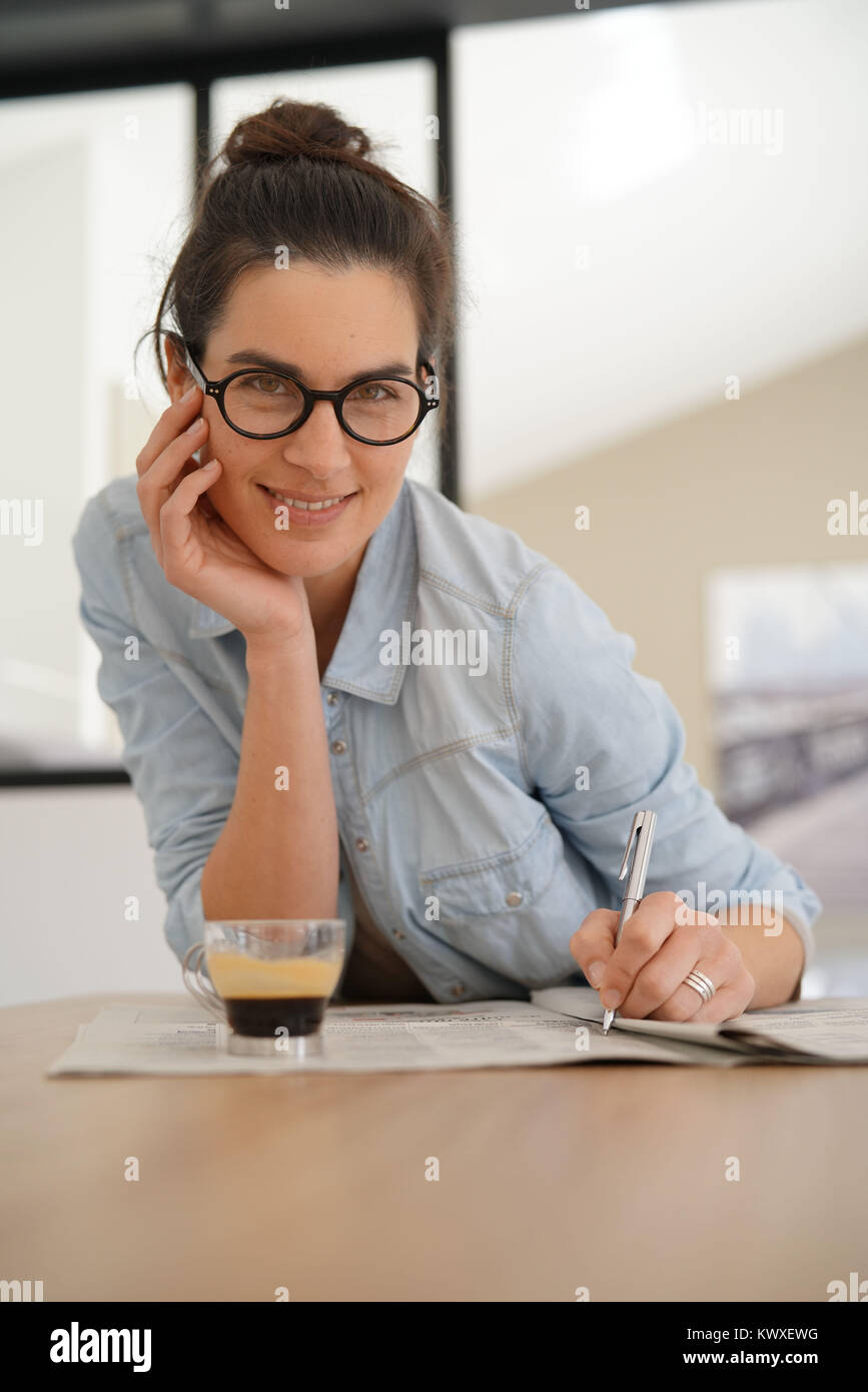 Brunette girl at home reading newspaper Stock Photo - Alamy