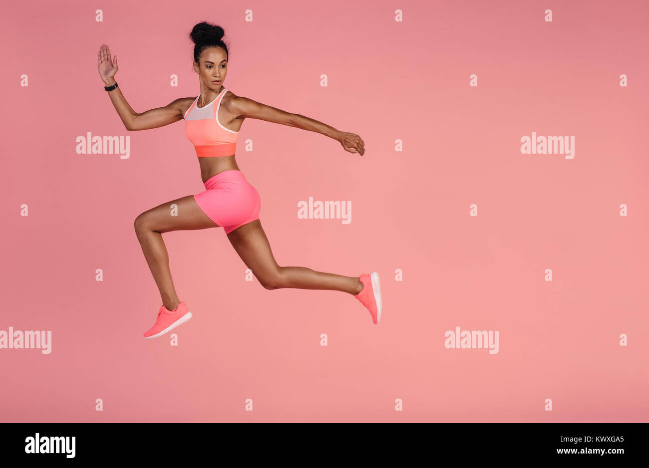 Woman in sportswear running over pink background. Full length shot of ...