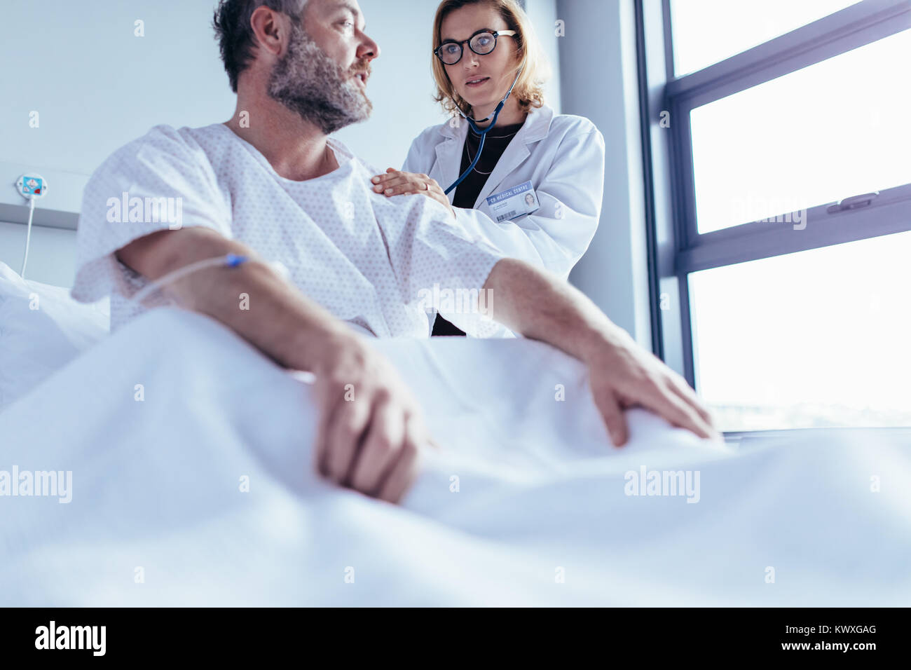Male patient getting examined in hospital room by female physician ...