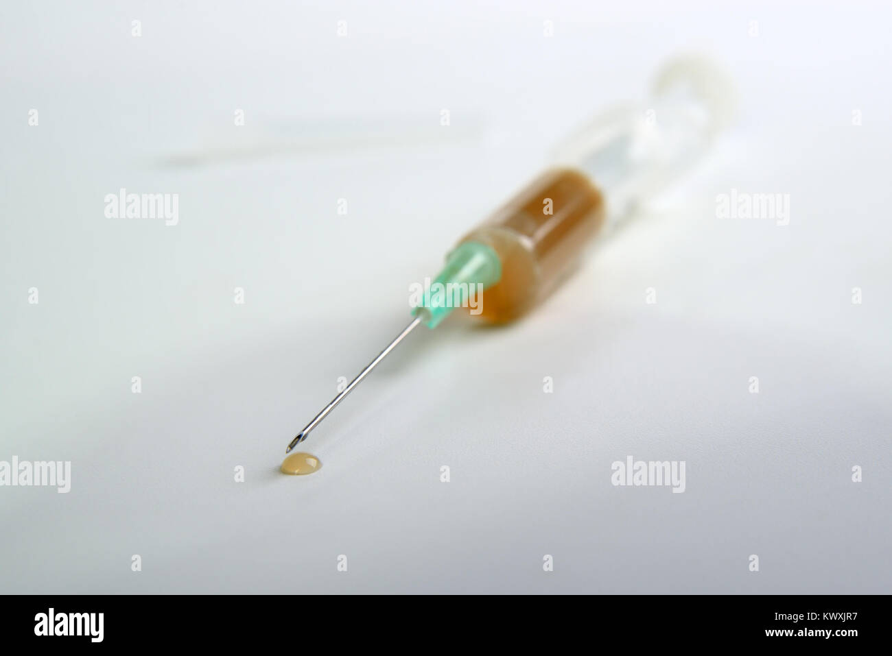 Medical disposable syringe with injection solution drop on white ...