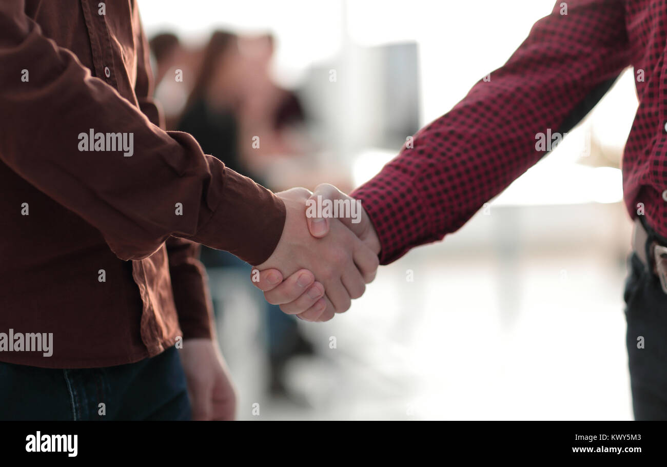 closeup of handshake between two men in the background of the office ...
