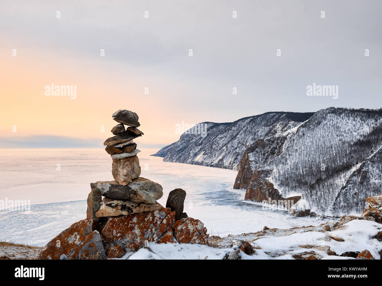 Pyramid of stones above ice lake. Dawn on Lake Baikal in March. Olkhon ...