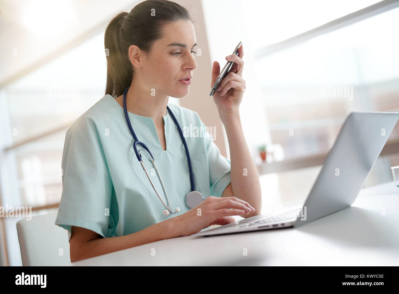 Nurse working on laptop computer and recording on dictaphone Stock ...