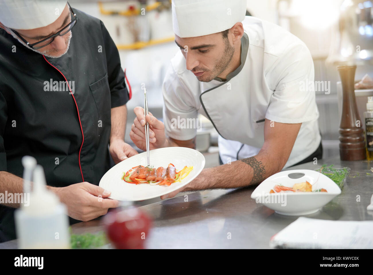 Professional cook chefs in kitchen improving dish composition Stock ...