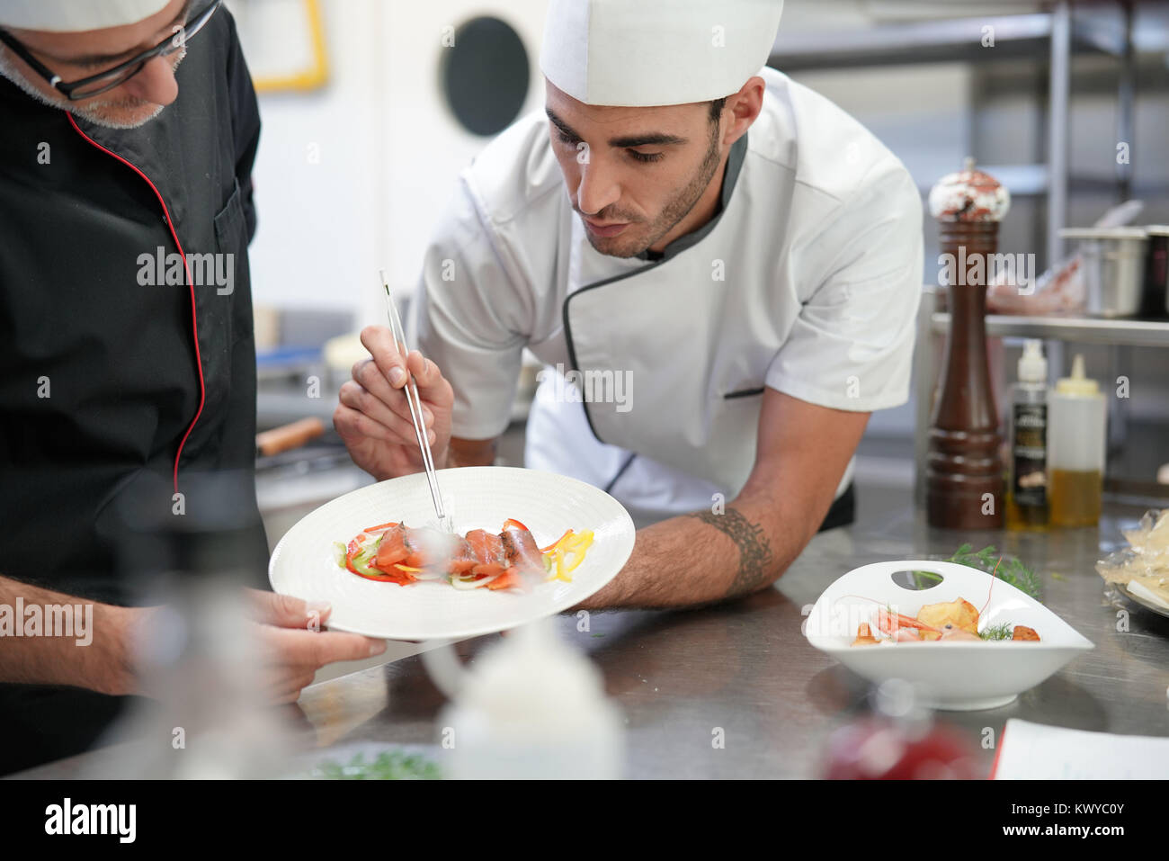 Professional cook chefs in kitchen improving dish composition Stock ...