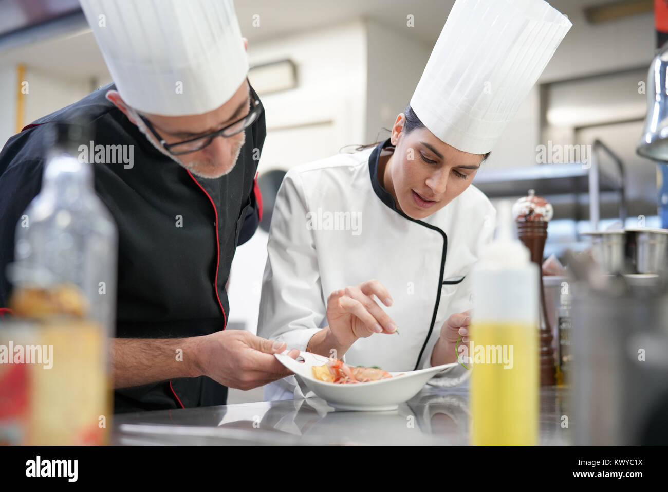 Professional cook chefs in kitchen improving dish composition Stock ...