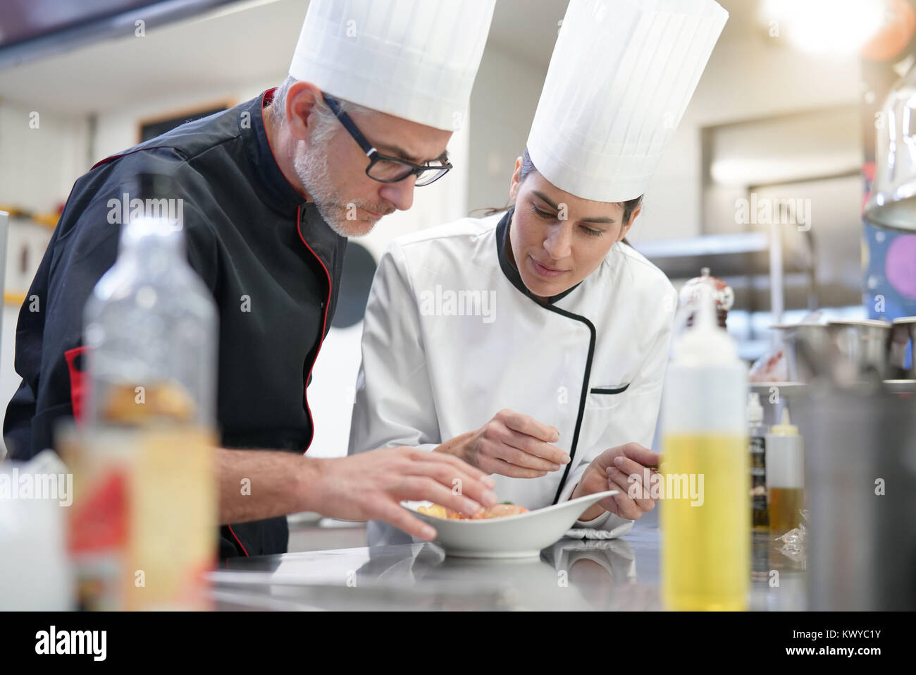 Professional cook chefs in kitchen improving dish composition Stock ...