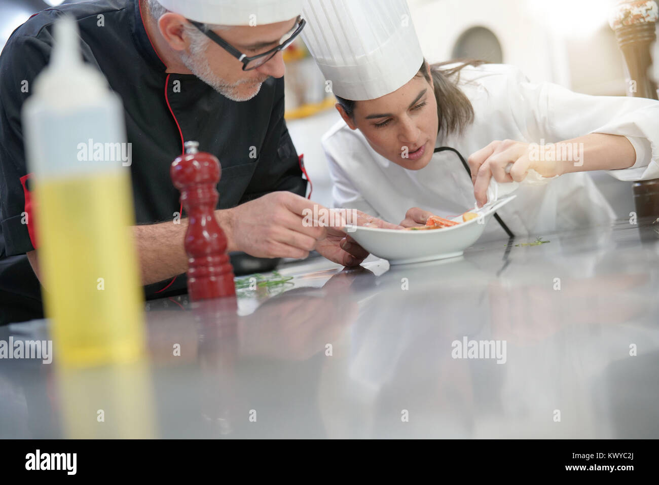 Professional cook chefs in kitchen improving dish composition Stock ...