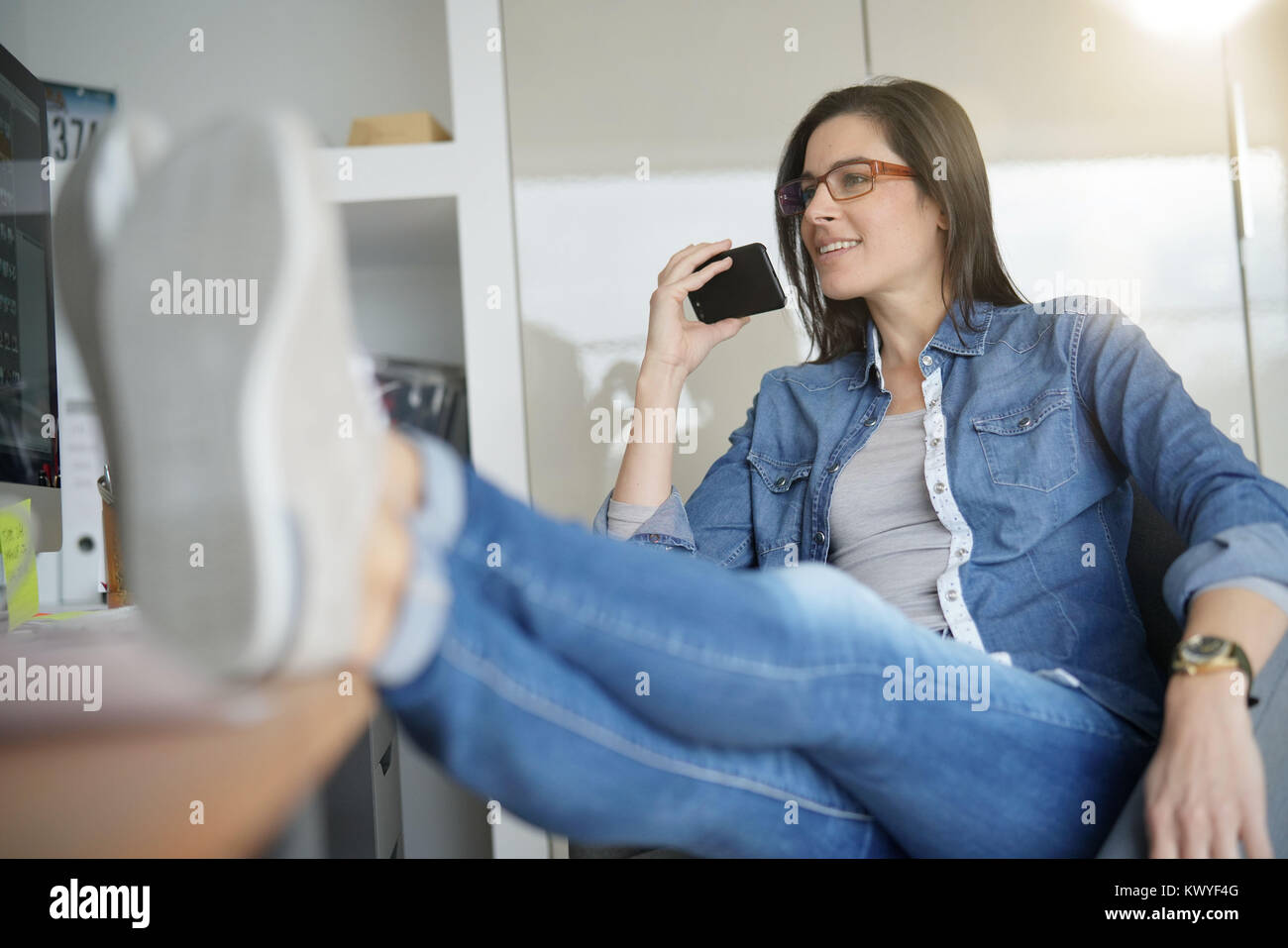 Office worker talking on phone, relaxing on chair Stock Photo - Alamy