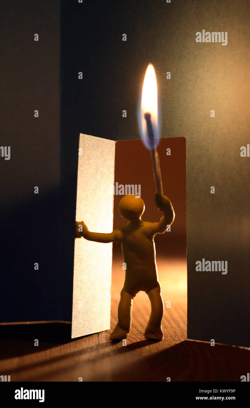 Yellow plasticine man with lighting match entering to dark room ...