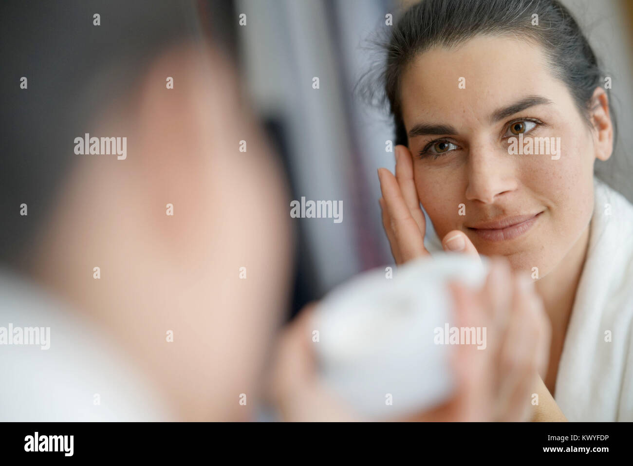 Woman in front of mirror applying cosmetics on Stock Photo - Alamy