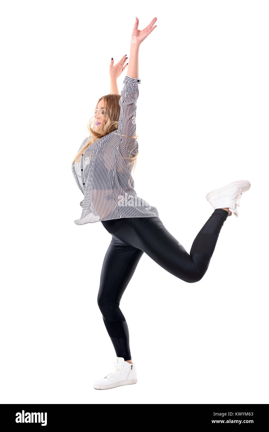 Cheerful casual woman jazz dancer jumping on one leg with arms raised ...