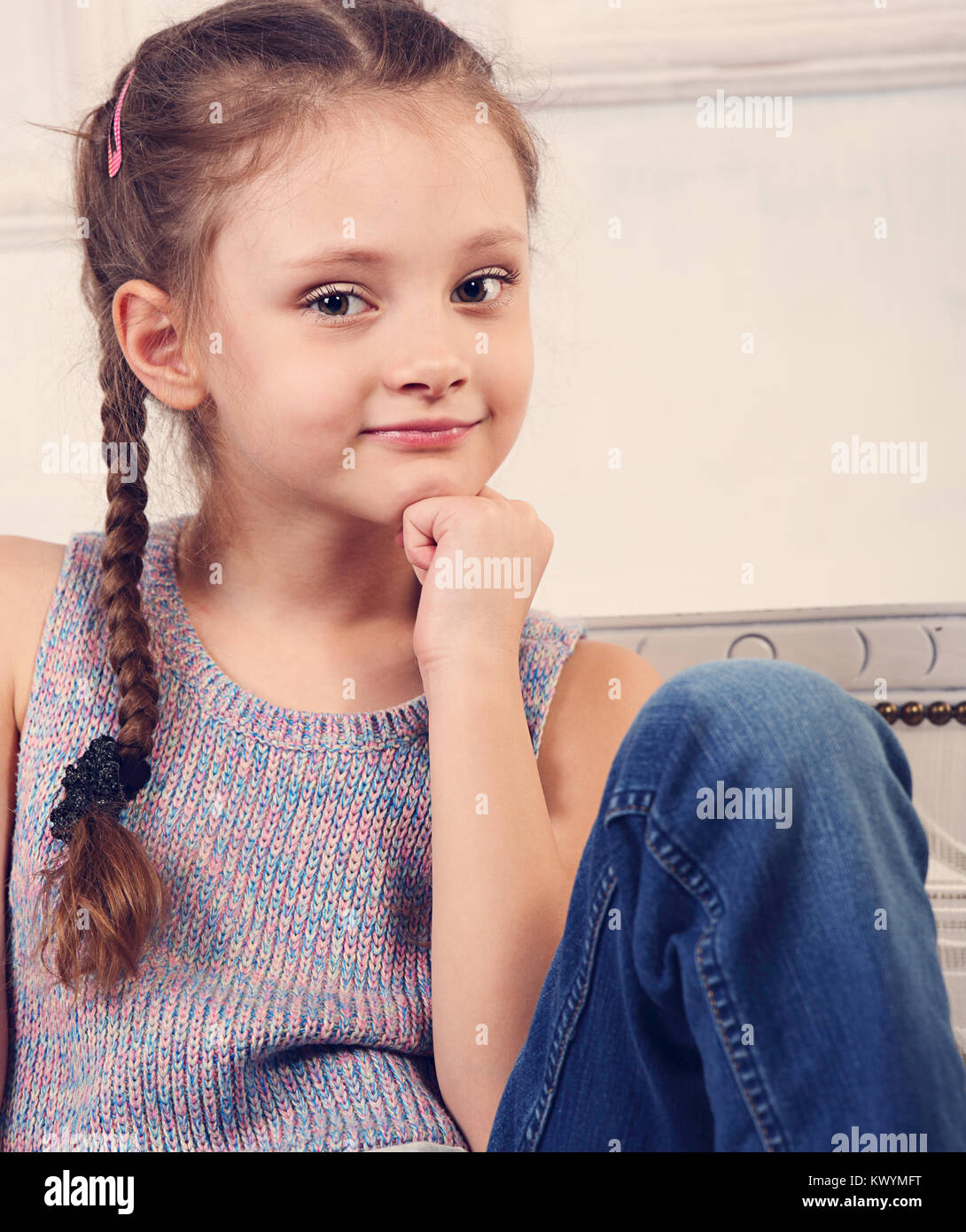 Beautiful thinking cute kid girl sitting on the bench in blue jeans and ...
