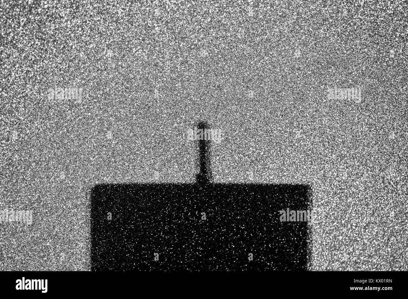 A black and white candle shadow with a wick on the top on a sparkly ...