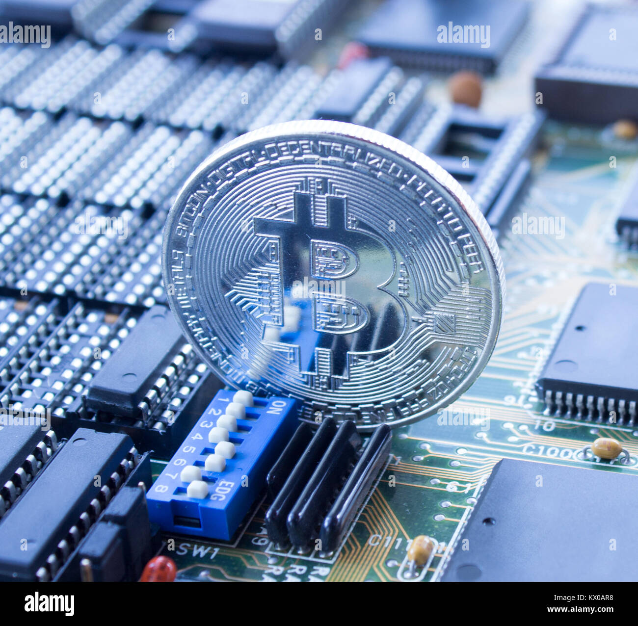 On a printed circuit motherboard is standing silver coin of a digital ...