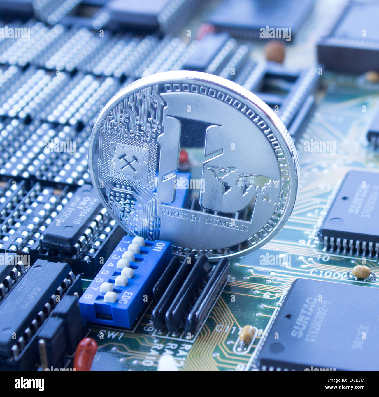 On a printed circuit motherboard is standing silver coin of a digital ...
