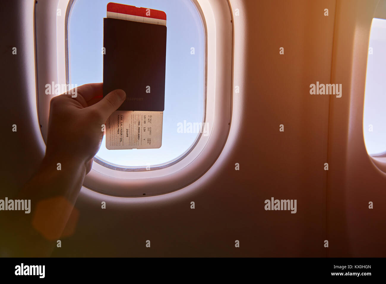 Hand hold passport in air plane on window with clear blue sky ...