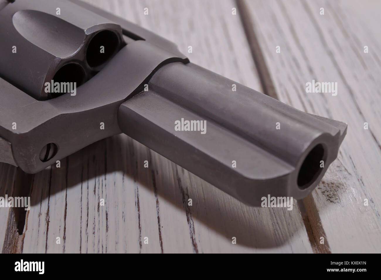 A close up of a barrel and cylinder of a stainless revolver on a white ...