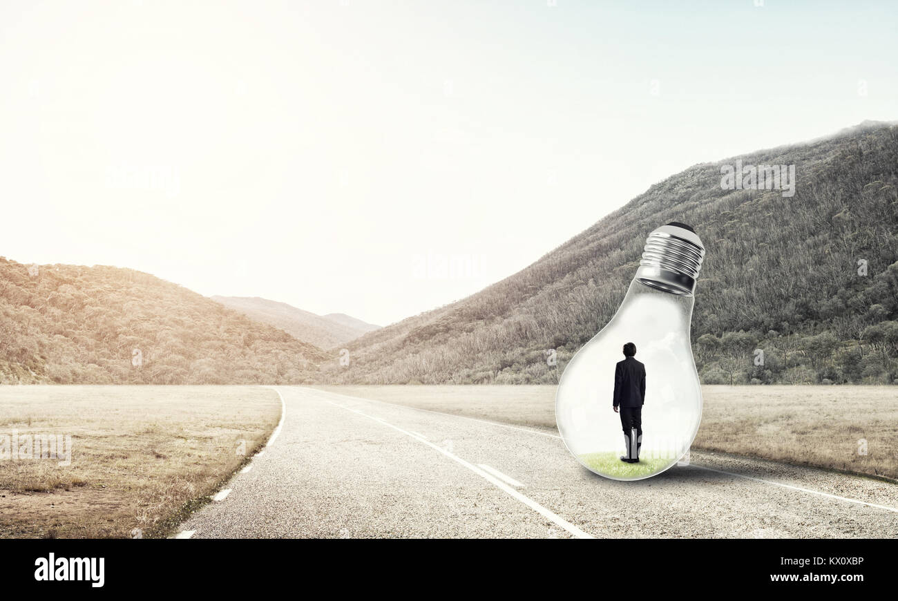Young businessman trapped inside of light bulb on asphalt road Stock ...