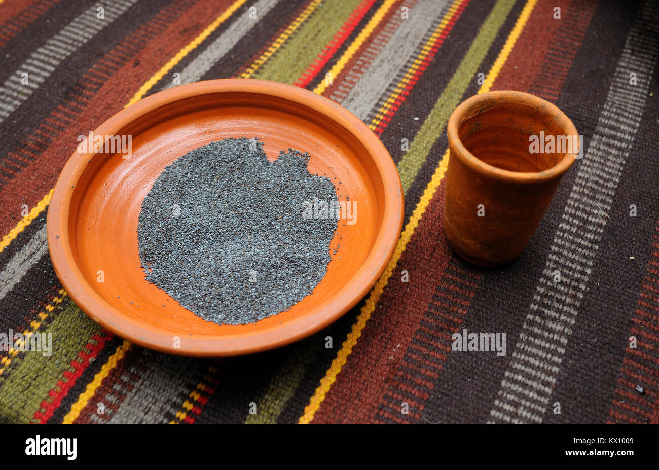 Ukrainian traditional clay plate with poppy on it and a clay cup placed ...