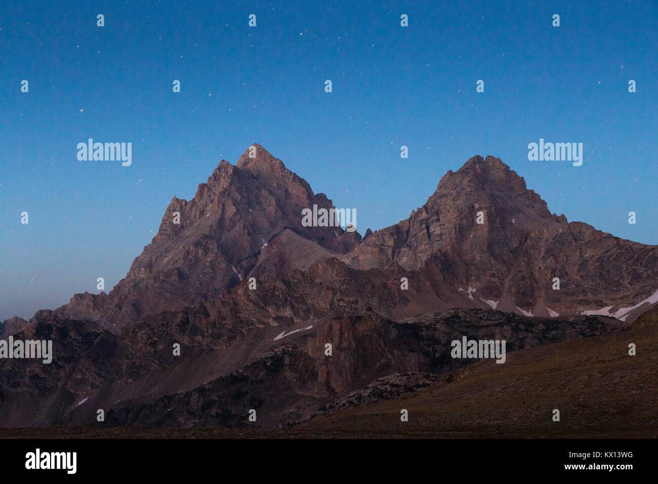 Stars emerging in a night sky above the Grand Teton and Middle Teton as ...