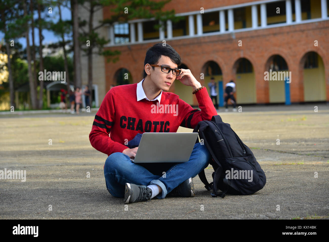 A young student sitting and thinking with laptop at an old college ...