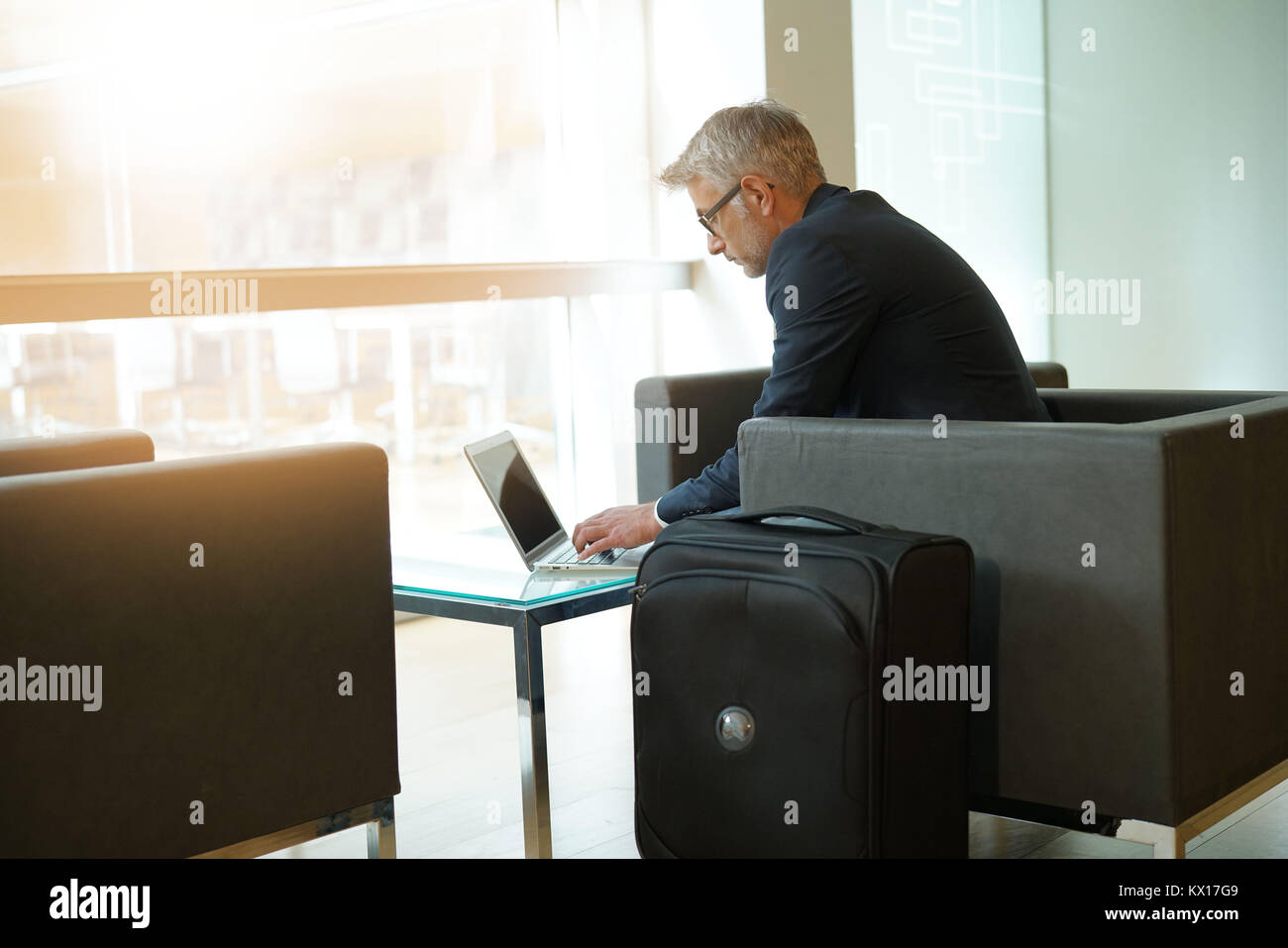 Businessman in waiting room connected with laptop Stock Photo - Alamy