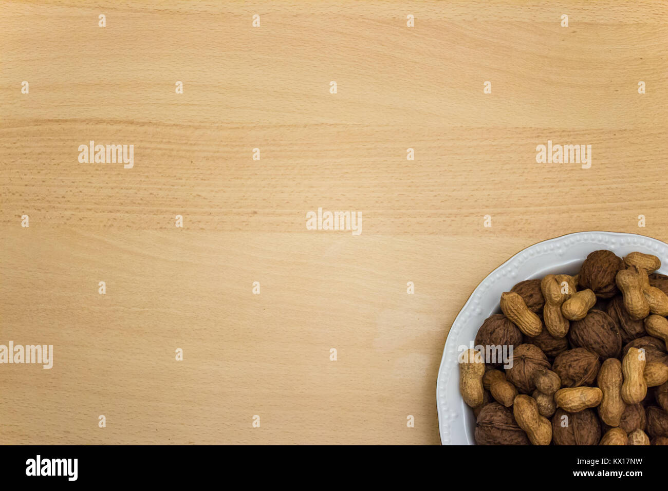plate of nuts in corner of wooden table with empty space Stock Photo ...