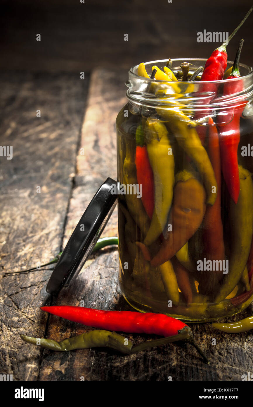 Pickled hot chili peppers in glass jar. On a wooden background Stock ...