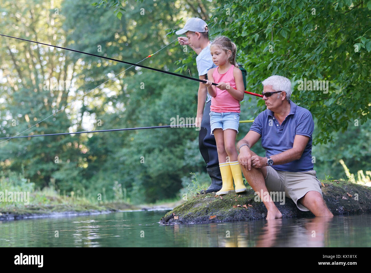 Dad teaching kids how to fish in river Stock Photo - Alamy