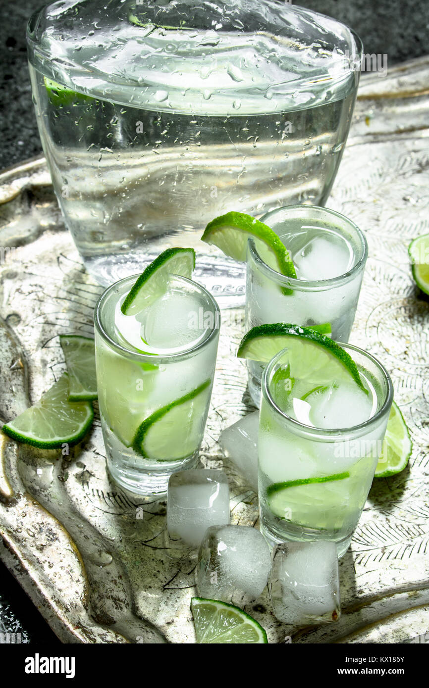 Vodka with lime and ice on a steel tray. On a rustic background Stock ...