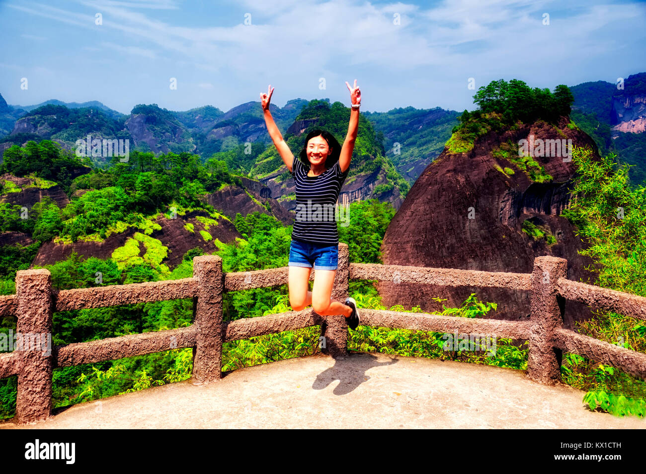 A chinese woman jumping with the landscape of the mountains and hills ...