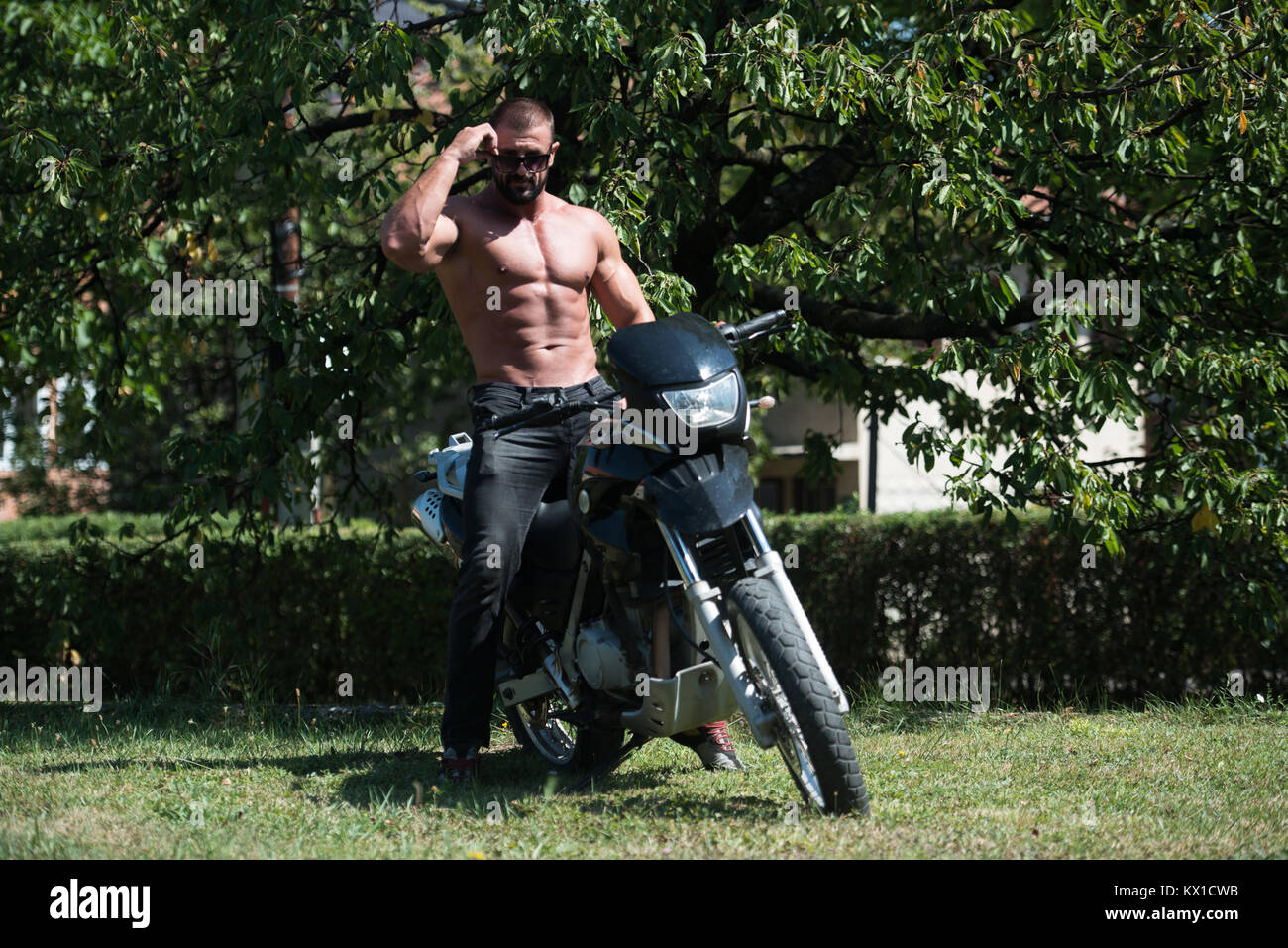 Biker Man Bodybuilder Sits On A Bike Stock Photo - Alamy