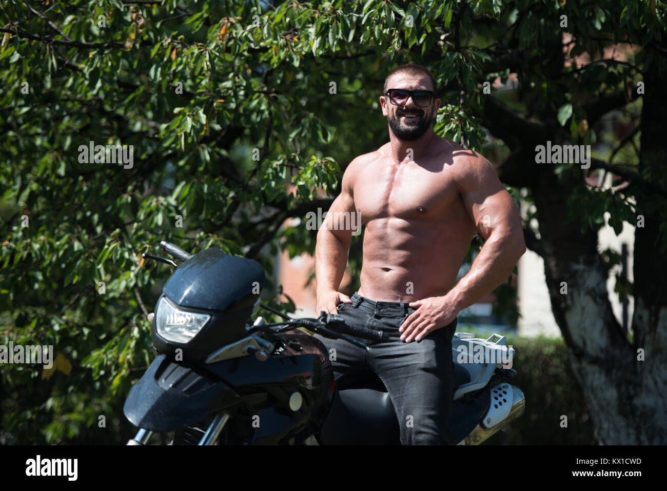 Biker Man Bodybuilder Sits On A Bike Stock Photo - Alamy
