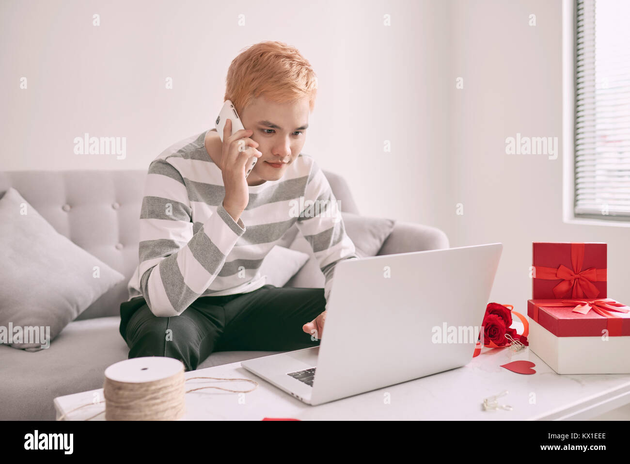Handsome guy holding red rose, call from girlfriend Stock Photo - Alamy
