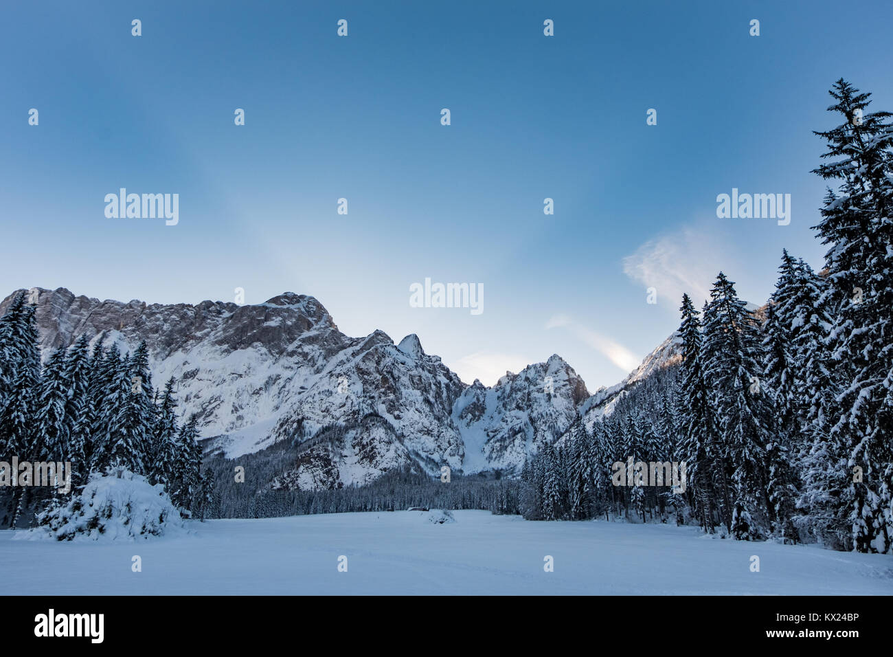 Mangart mountain range and forest seen from snow covert frozen lake ...