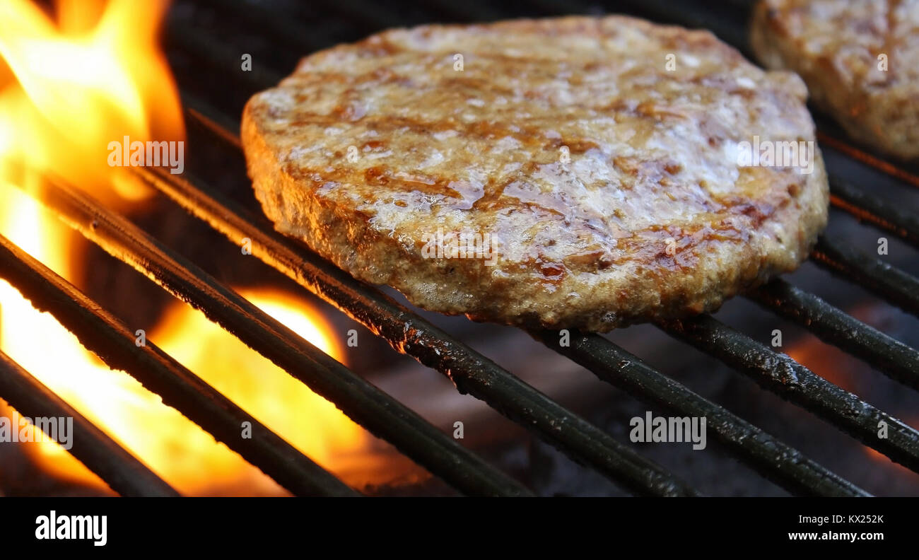 Burgers Cooking Over Flames On The Grill Stock Photo - Alamy