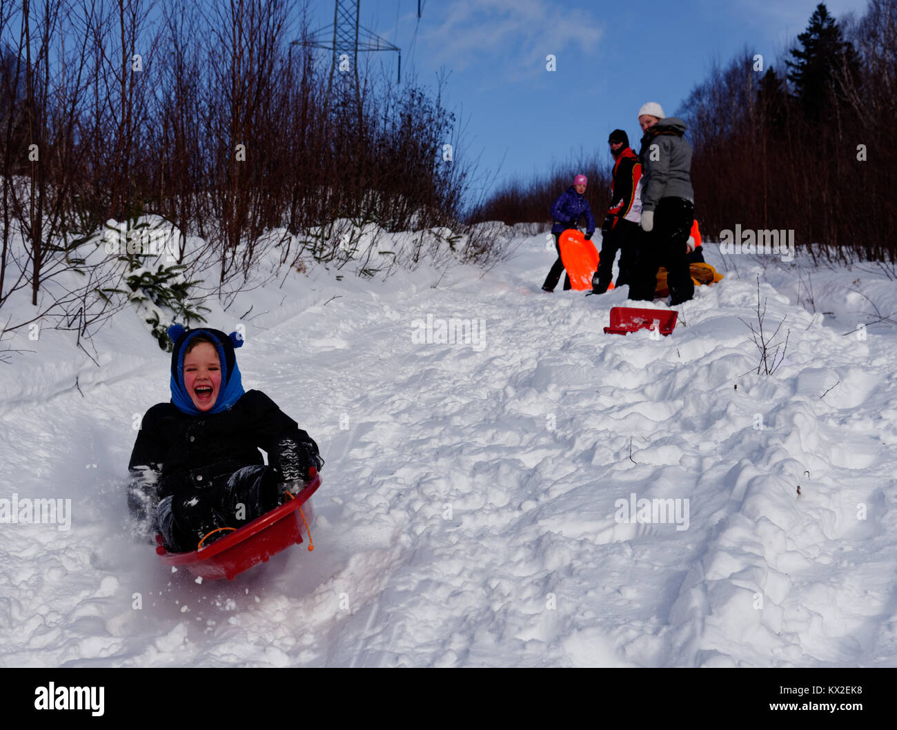 A laughing 5 yr old boy speeding on a sledge while the rest of the ...