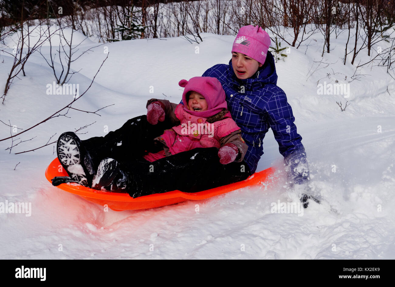 A teenager (18 yr old) in a sledge with a young child (3 yr old ...